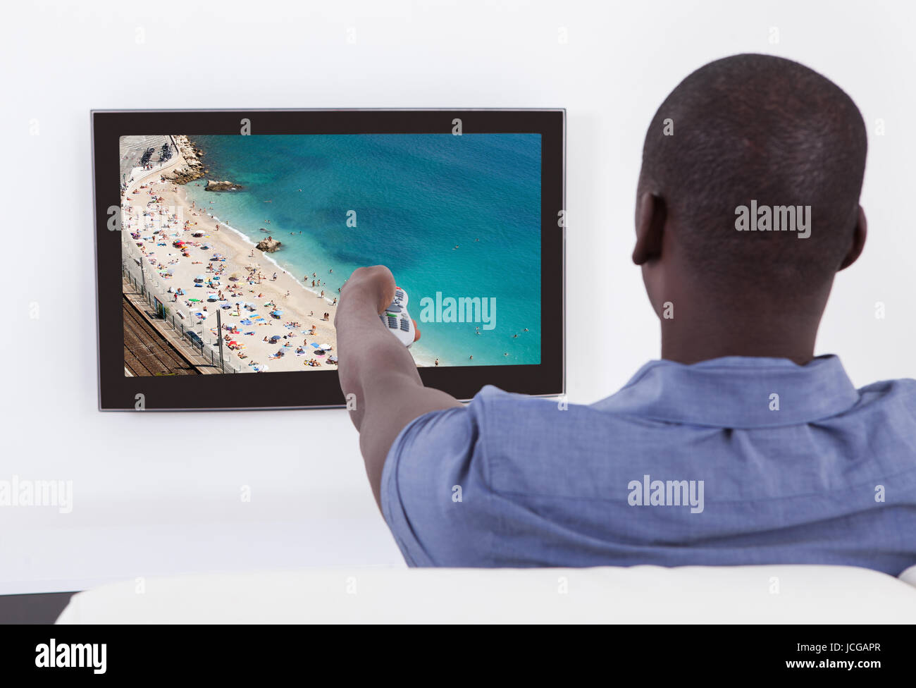 Rear View Of African Man Changing Channel With Remote Stock Photo - Alamy