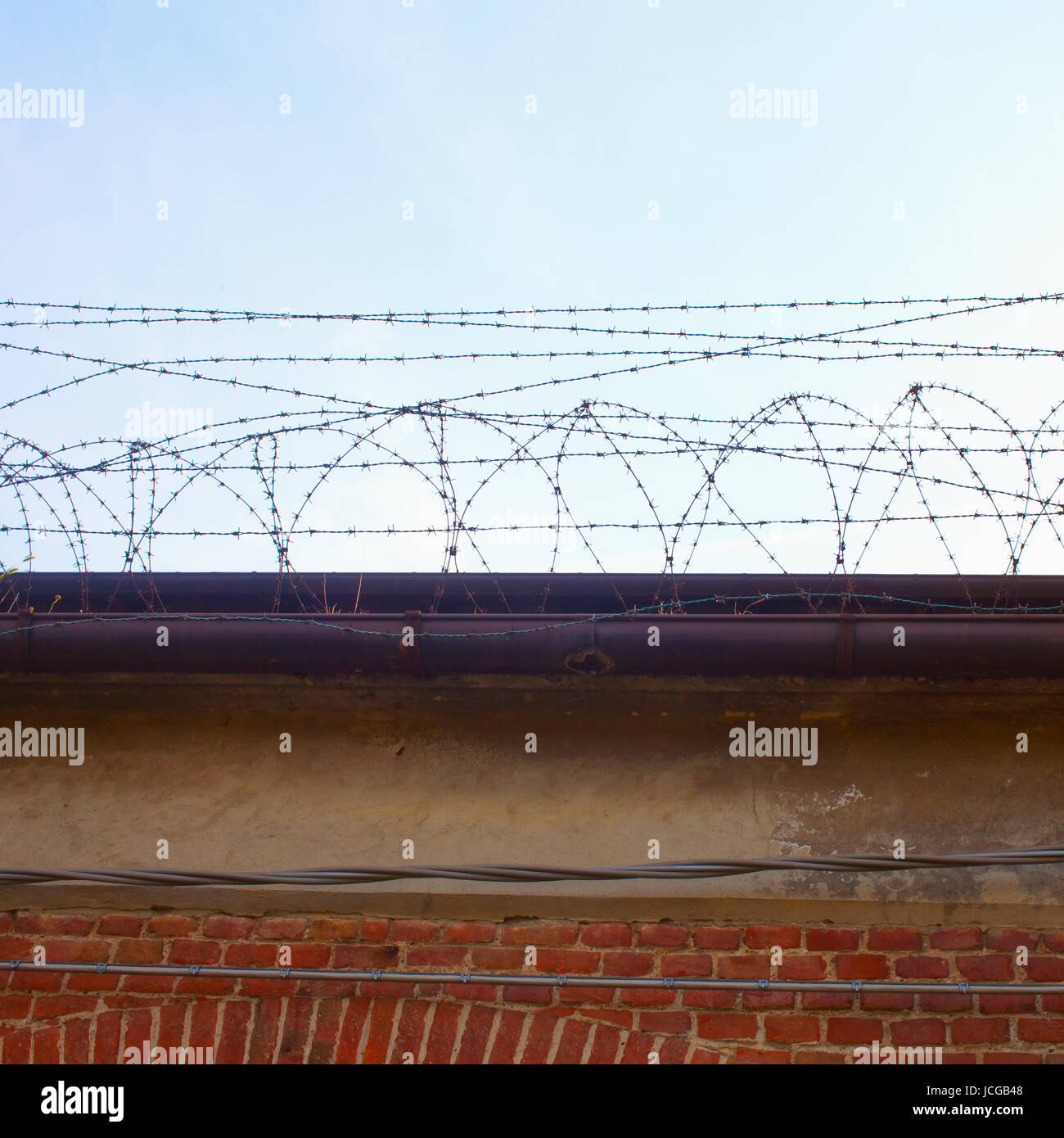 Barb wire on top of a wall, blue sky Stock Photo - Alamy