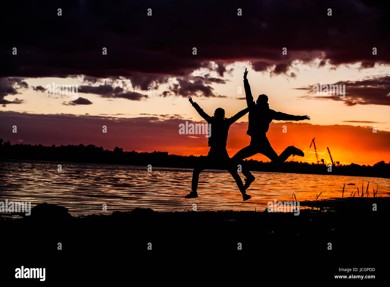 Happy jumping couple on the tropical sunset background Stock Photo - Alamy