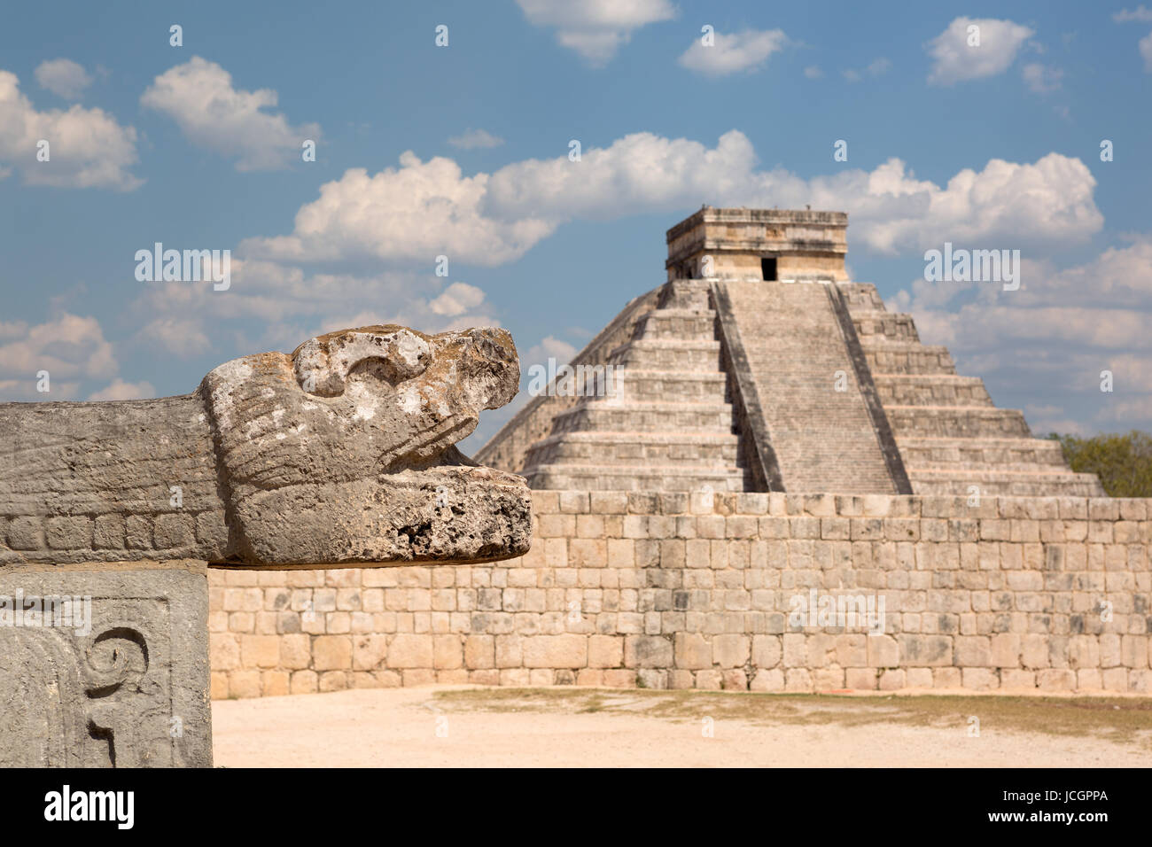 Mayan stone snake head sculpture with the pyramid of Kukulcan in the ...