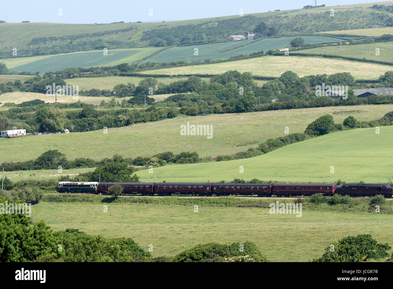 Diesel engine pulling passenger coaches through the Dorset countryside ...