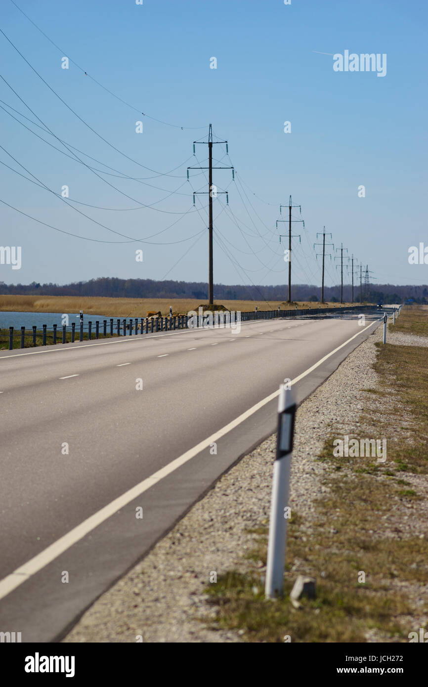 Straight road and high-voltage power transmission line against blue sky ...