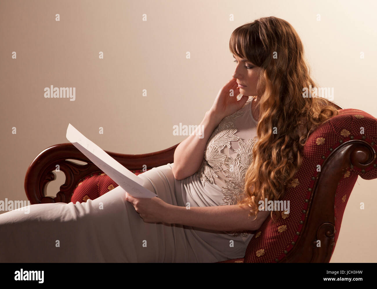 Attractive lady reading letter on couch Stock Photo - Alamy