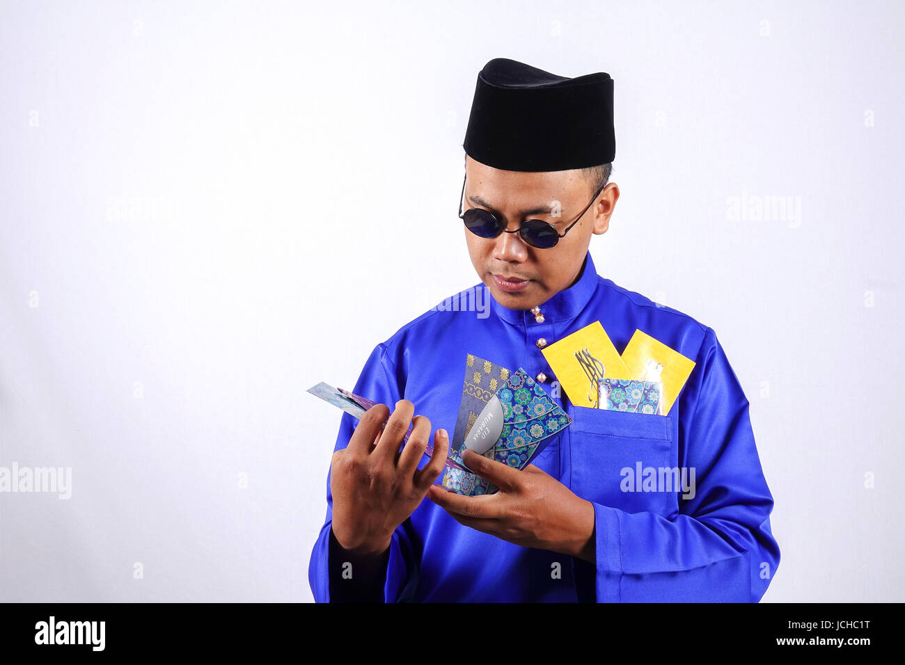 Man in traditional clothing cheerful with money packet during celebrate ...
