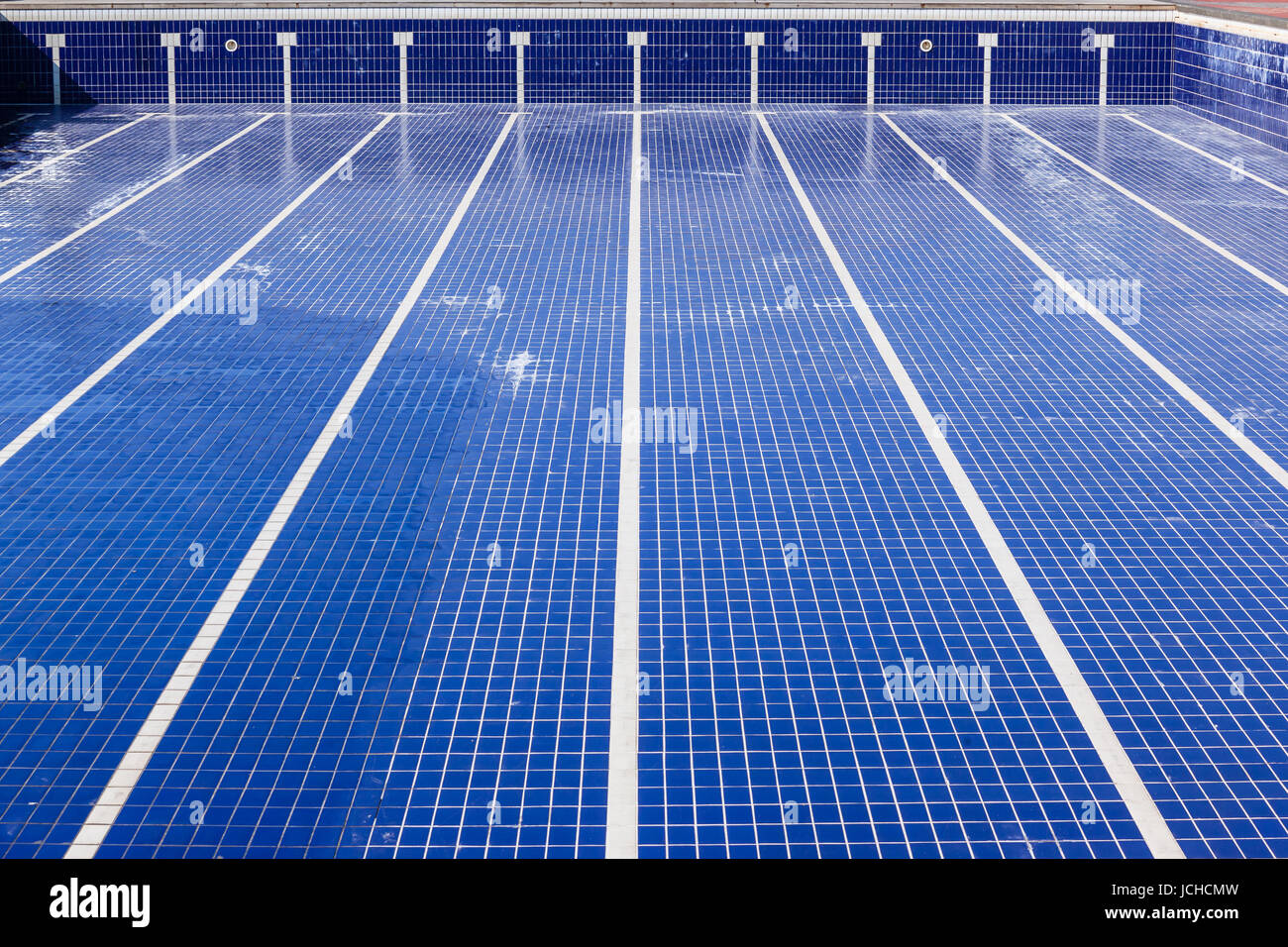Swimming pool with blue ties and swim lane tile markings empty of water ...