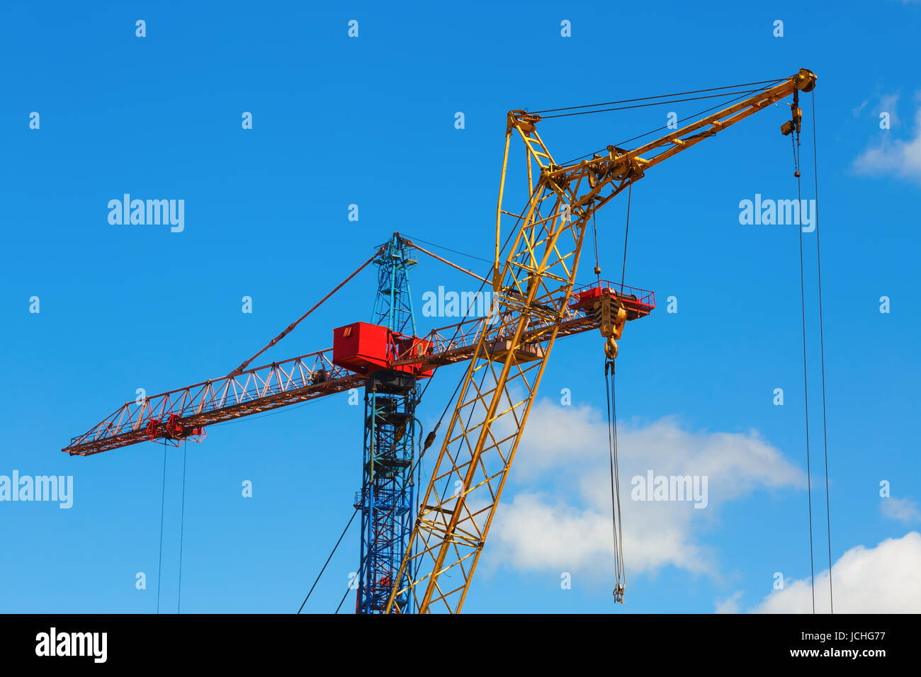 Tower crane and mobile construction crane against blue sky background ...
