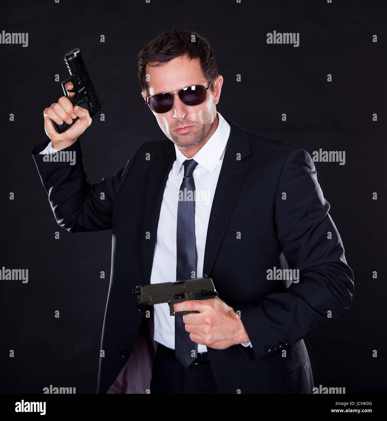 Portrait Of Young Man With Gun On Black Background Stock Photo - Alamy