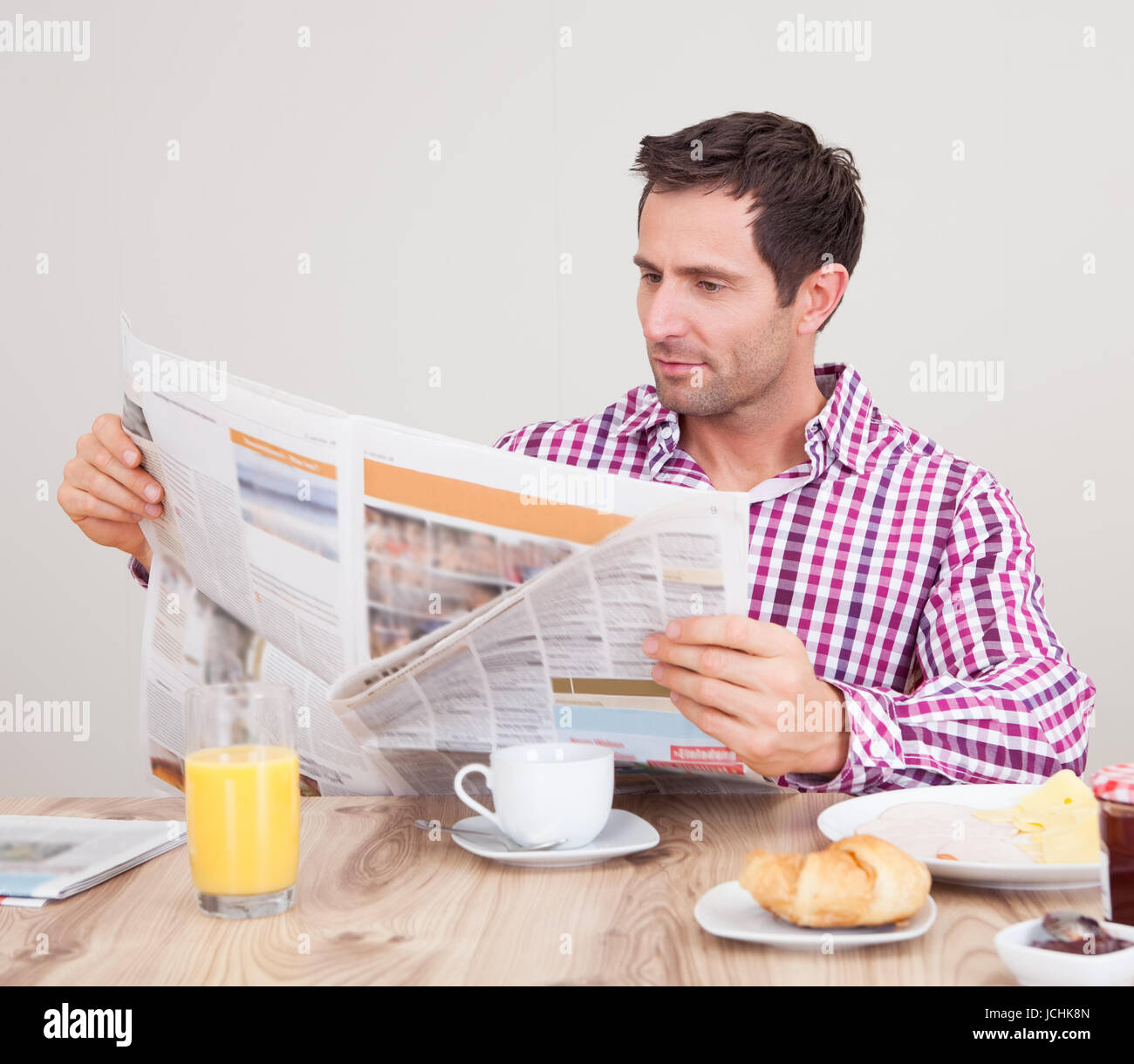 Portrait Of Young Man Reading Newspaper At Breakfast, Indoors Stock ...