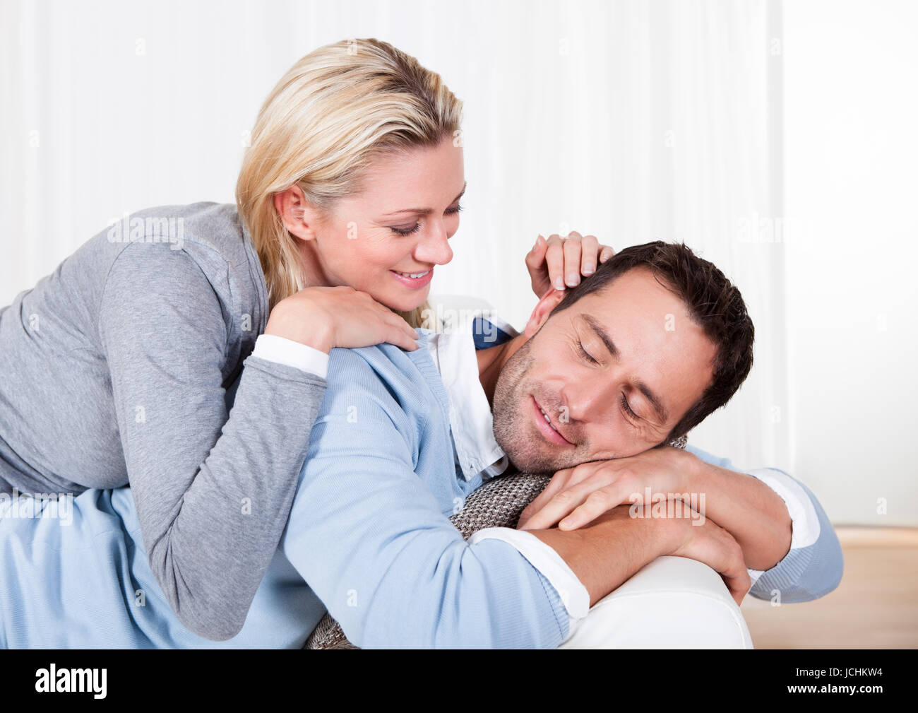 Happy attractive young man and woman smiling and cuddling as he relaxes ...