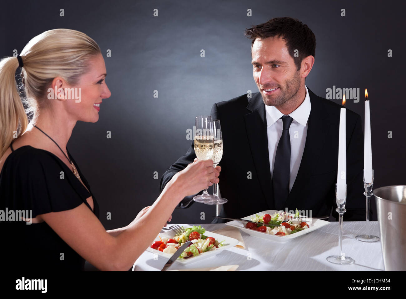 Romantic couple sitting having dinner in an elegant restaurant toasting ...