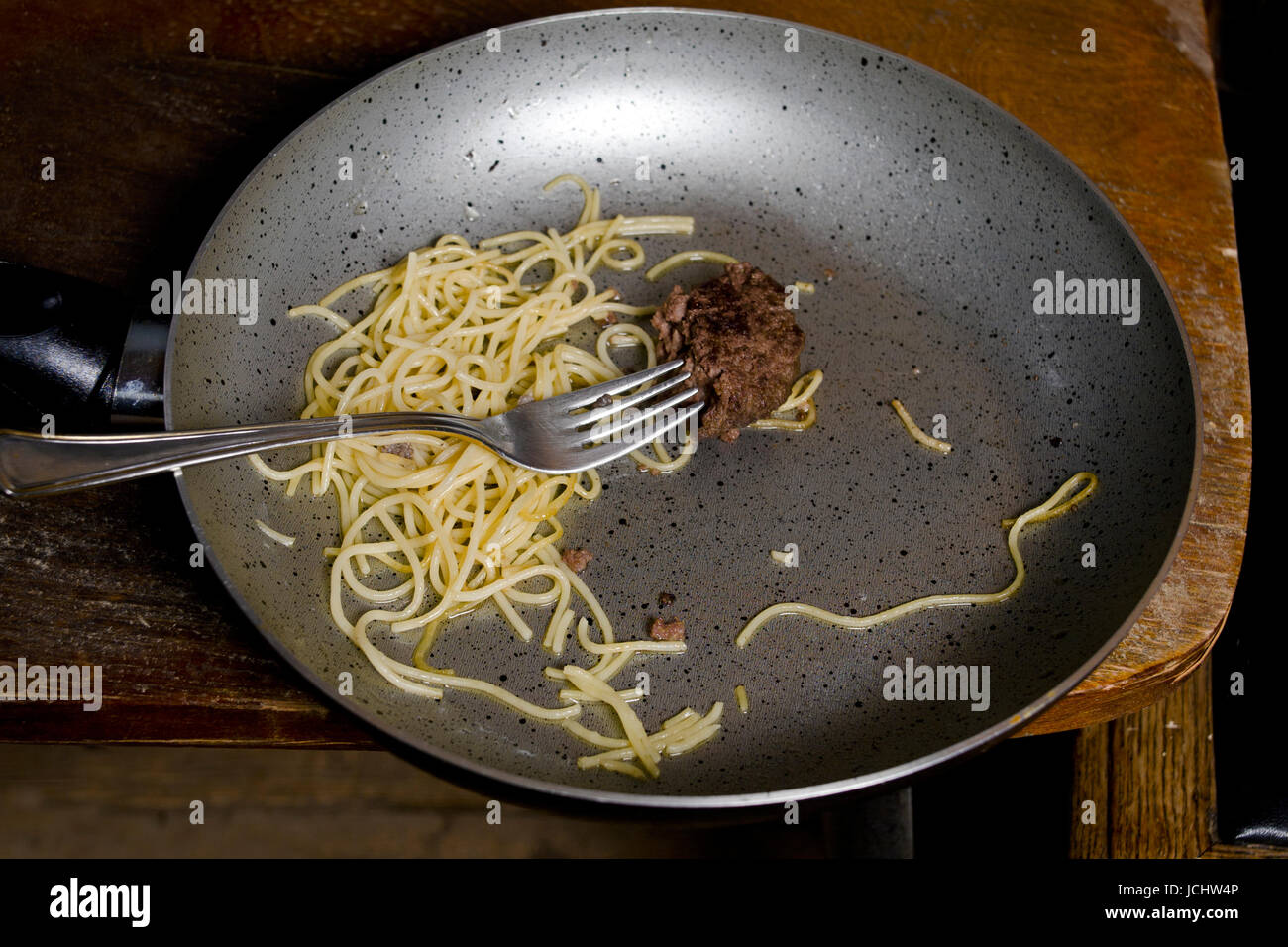 Unfinished food in a frying pan on a table top, concept of being a ...