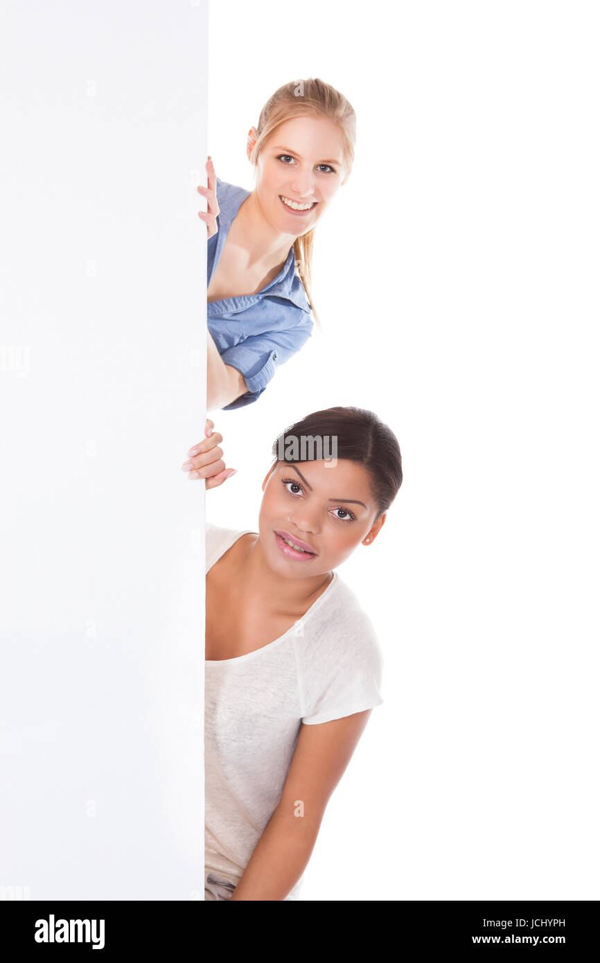 Two Female Looking From Behind The Blank Board Over White Background ...