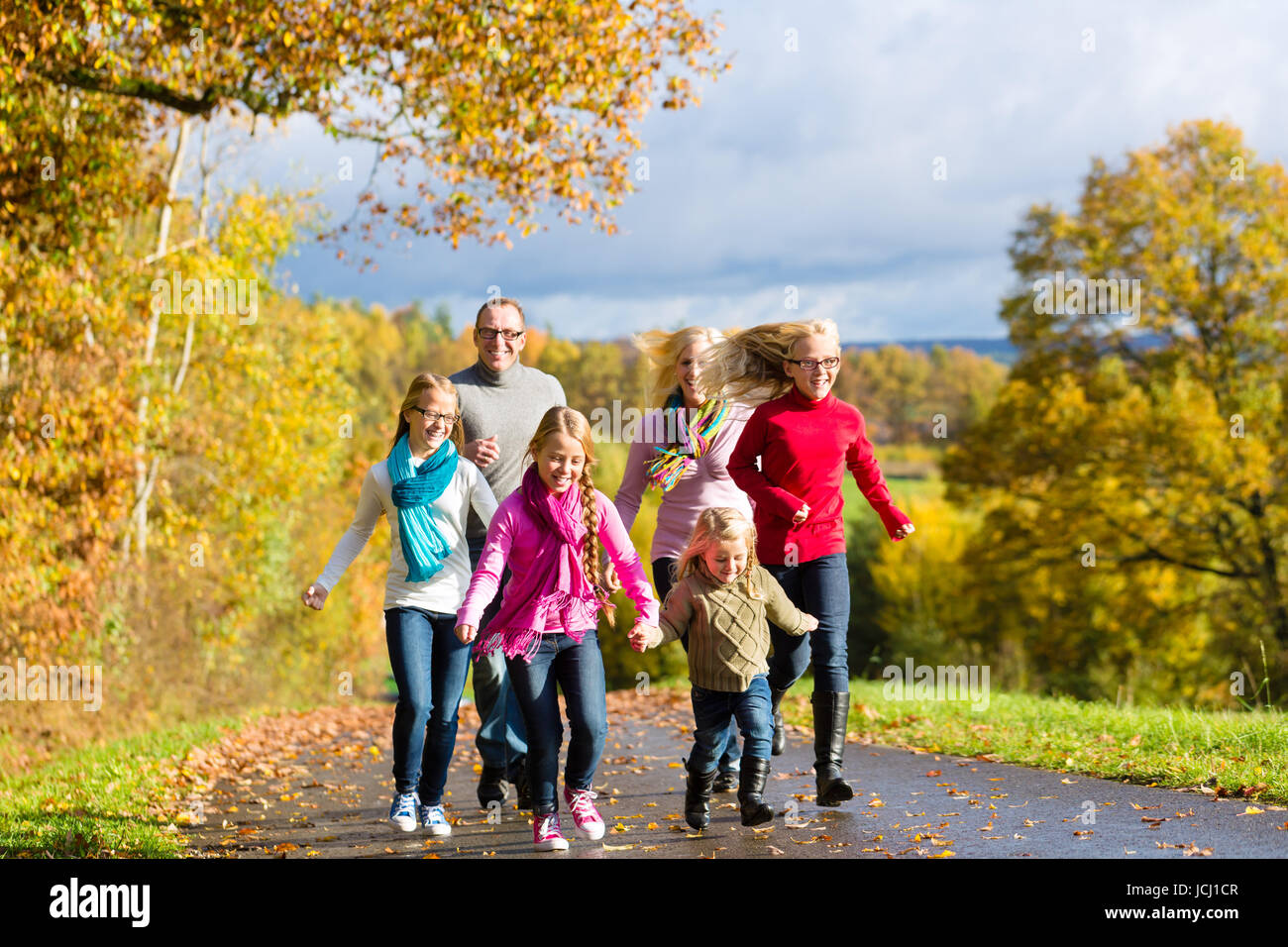 Girls running ahead at family walk through the park in fall or autumn ...