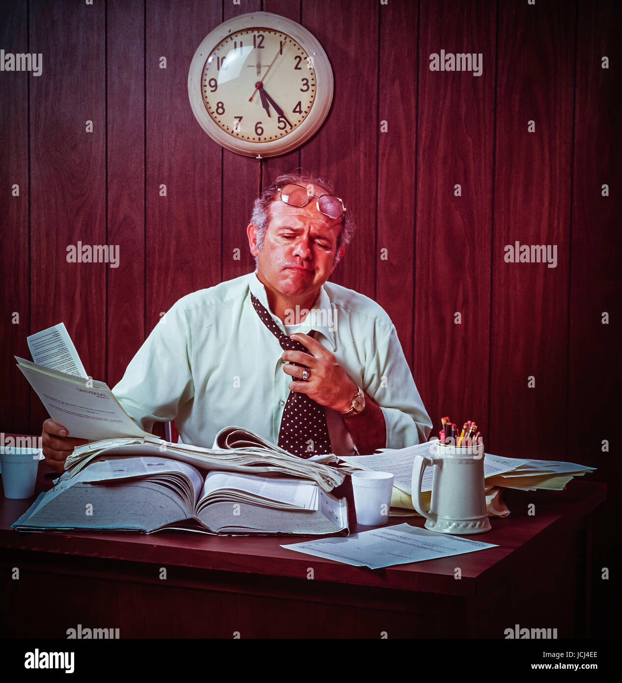 Exasperated, frustrated, overworked amid pikes of paperwork on desk ...