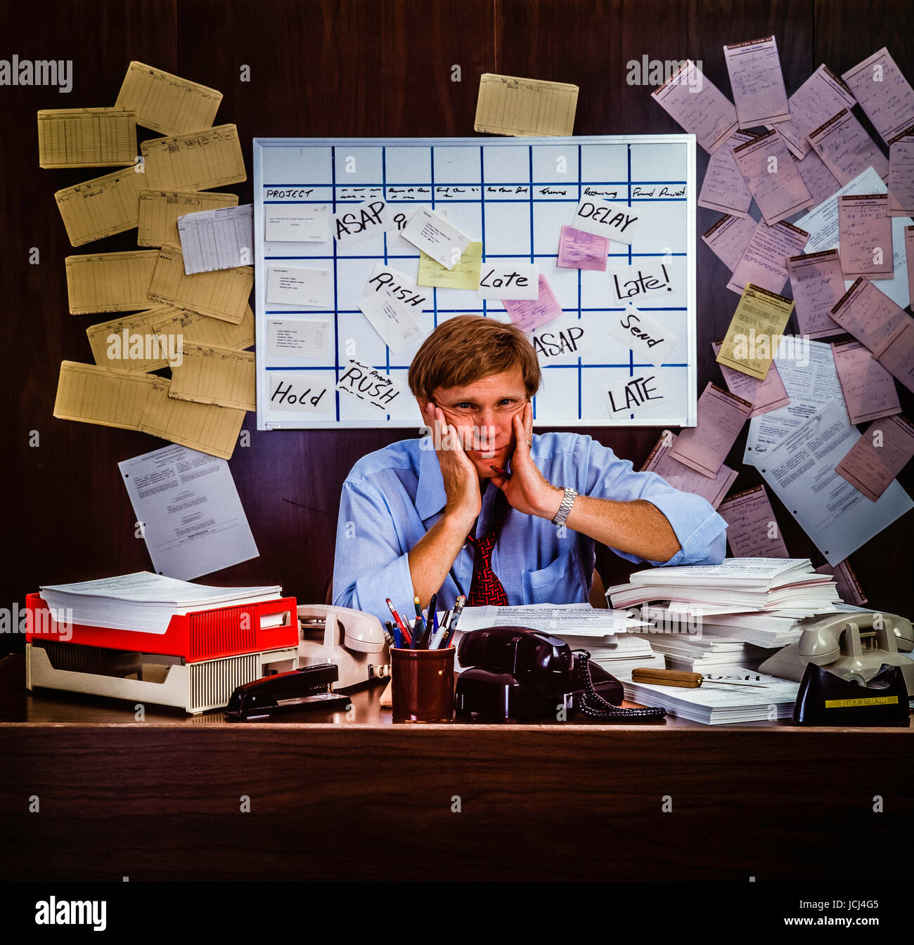 Exasperated, frustrated, overworked amid pikes of paperwork on desk ...