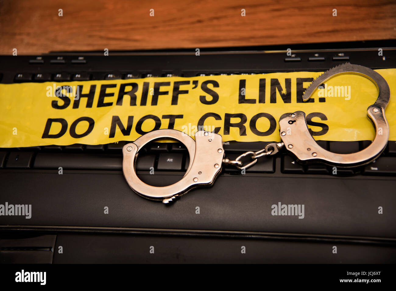 Handcuffs and crime scene tape rest on a computer keyboard Stock Photo ...
