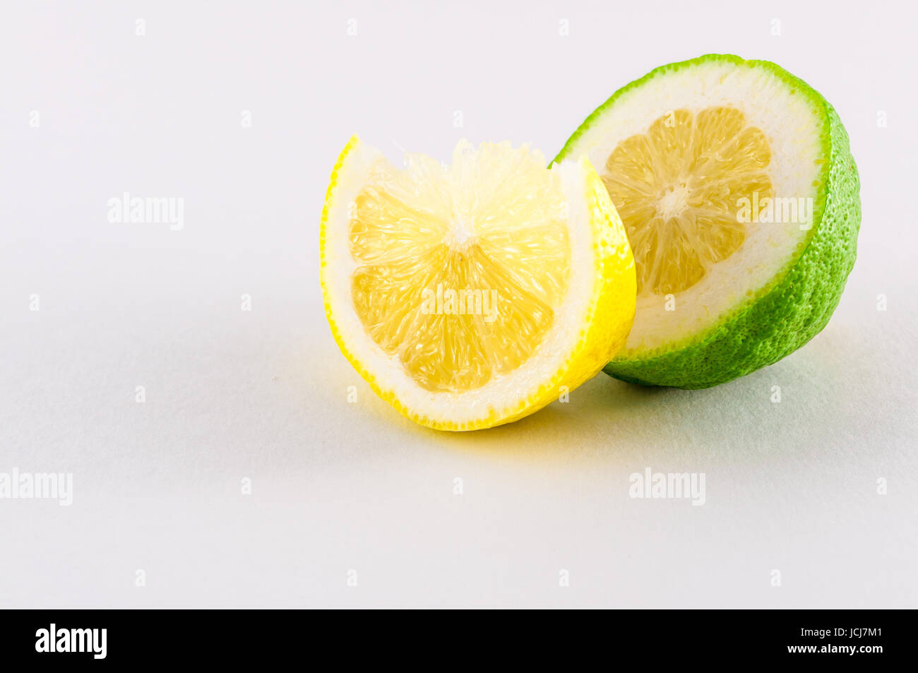 Slice of fresh lemons yellow and green on white background Stock Photo ...