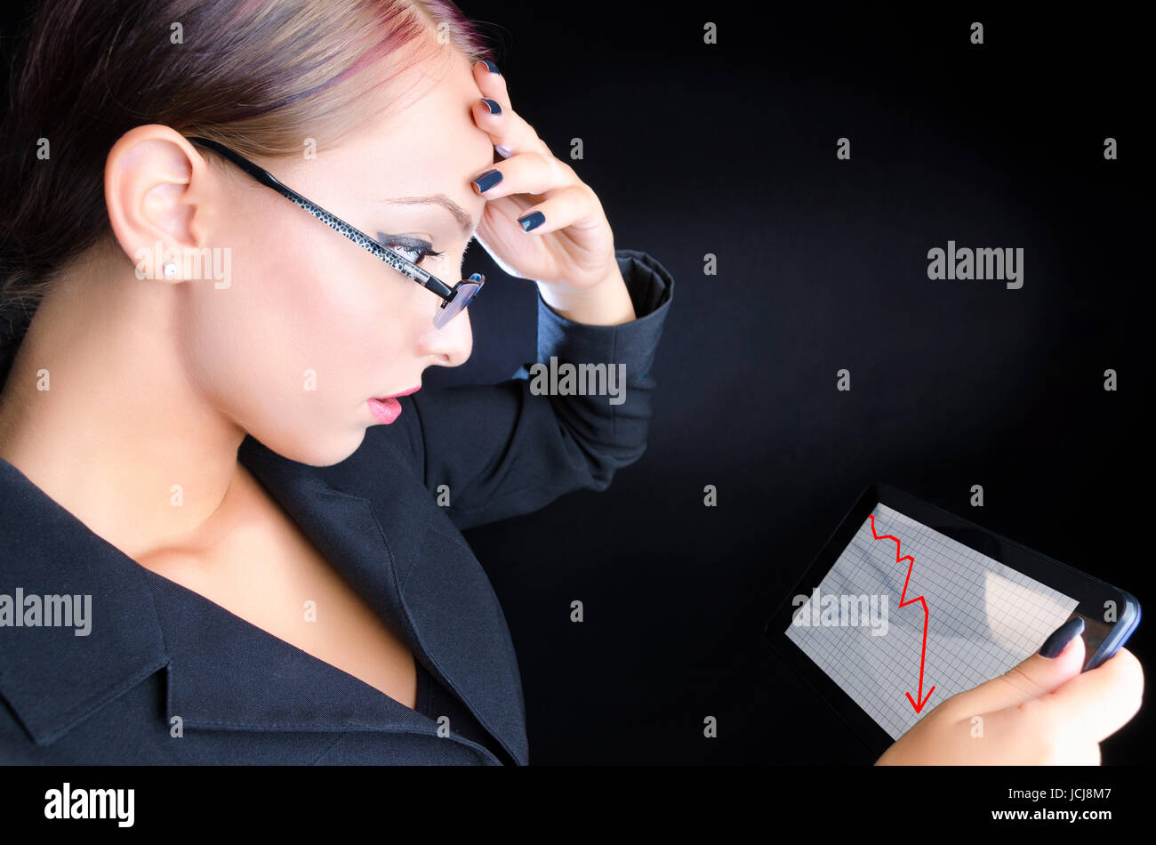 Attractive, young business woman looking at a descending graph on a ...