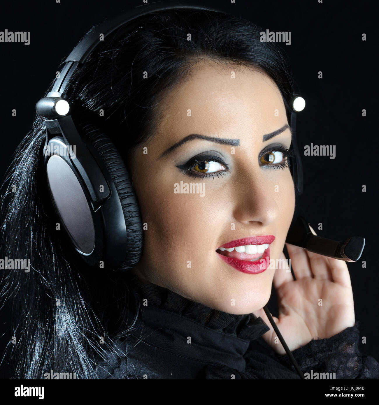 Attractive girl with headset against a black background Stock Photo - Alamy