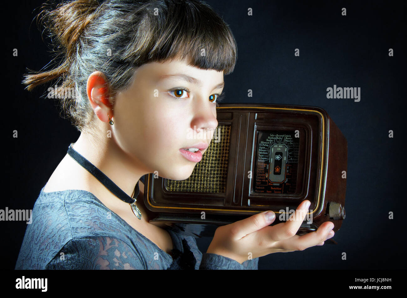 Girl holding/listening to an old radio against a black background Stock ...
