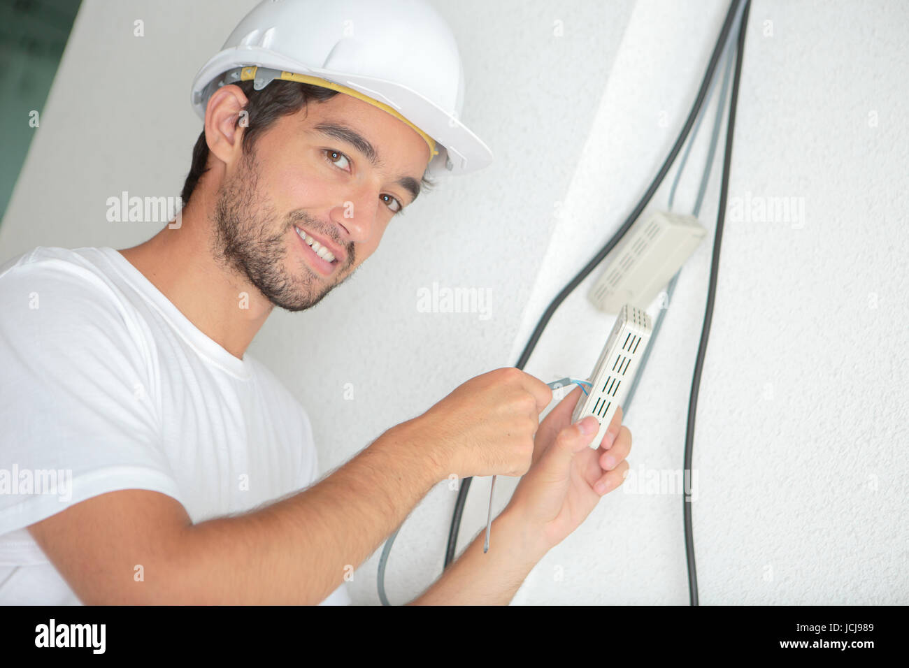 handsome electrician wiring to the wall at construction site Stock ...