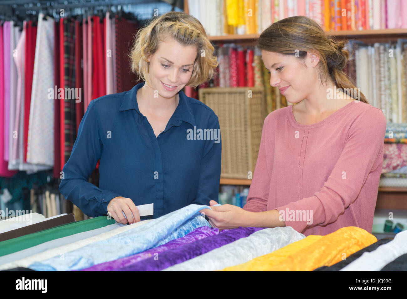 two smiling women selecting textiles in fabric store Stock Photo - Alamy