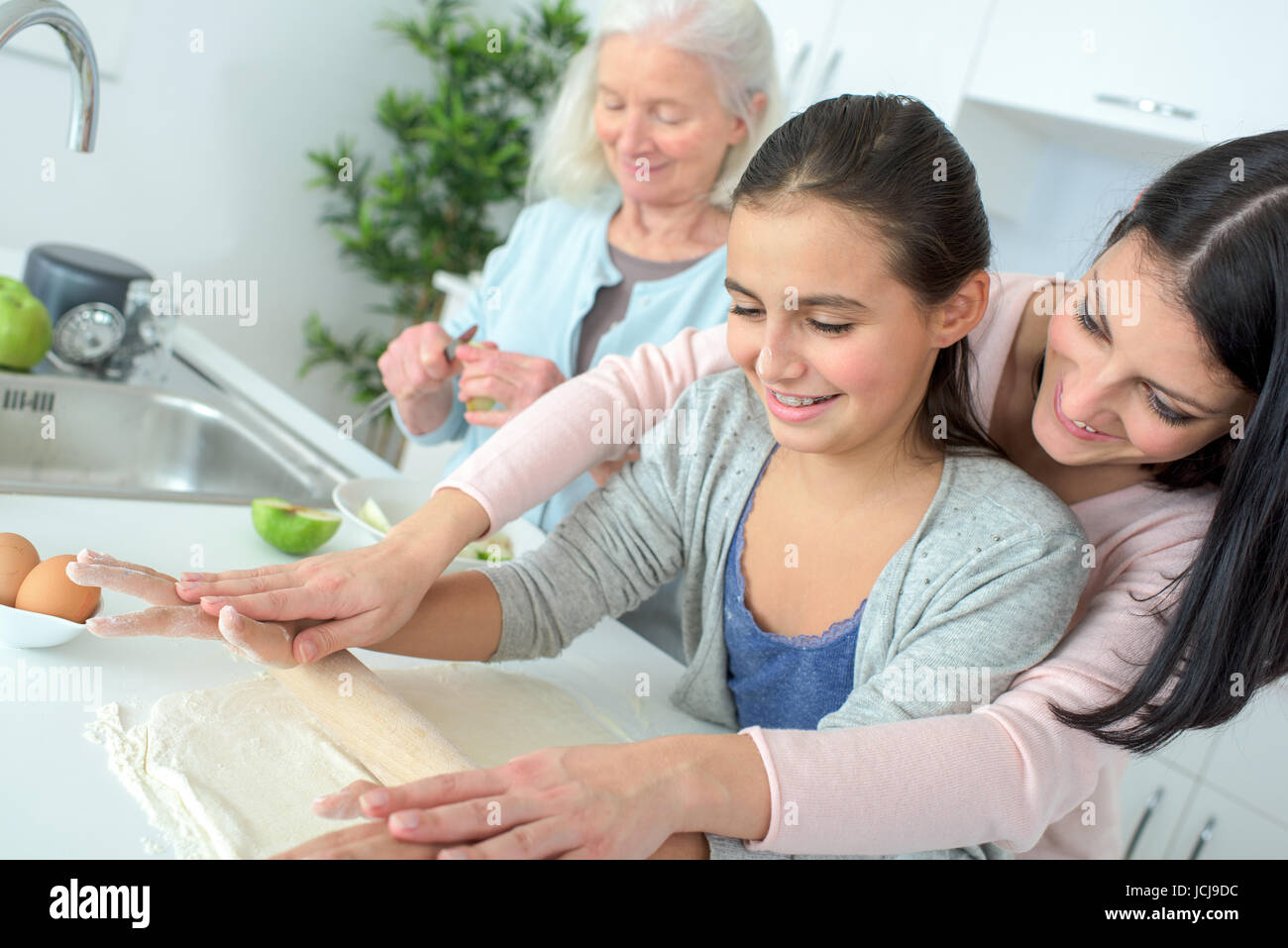 portrait of three generations of happy beautiful women cooking together ...