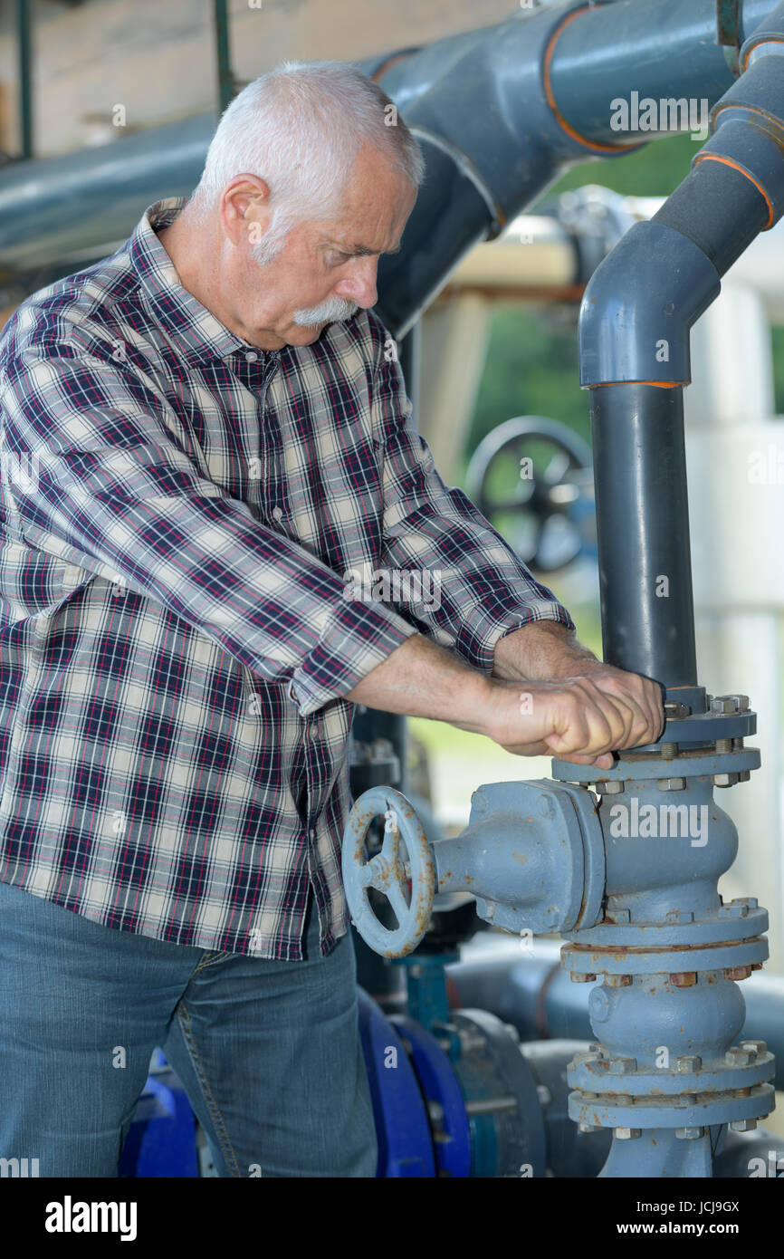 senior worker turning valve at plant Stock Photo - Alamy
