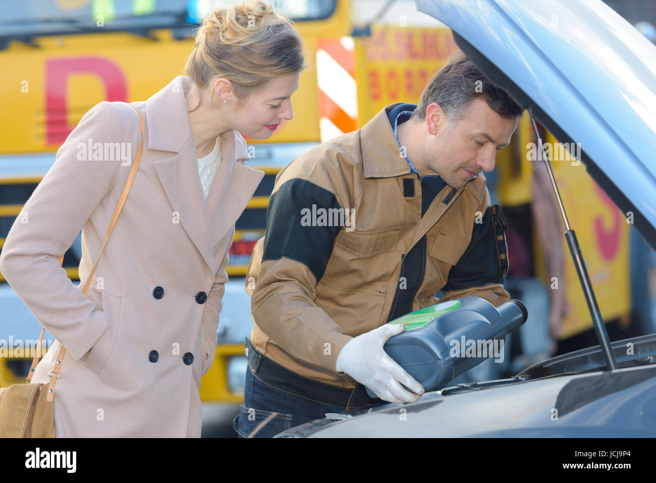 male mechanic filling oil tank of pretty woman customer Stock Photo - Alamy
