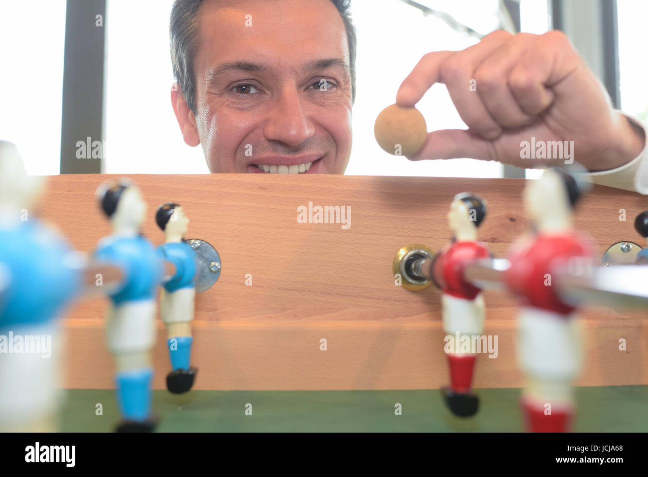 man at a table football smiling and holding ball Stock Photo - Alamy