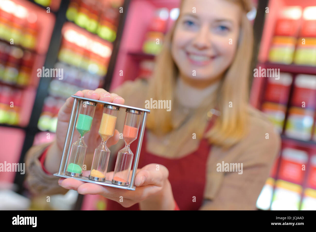 pretty sales assistant holding hourglass and smiling Stock Photo - Alamy