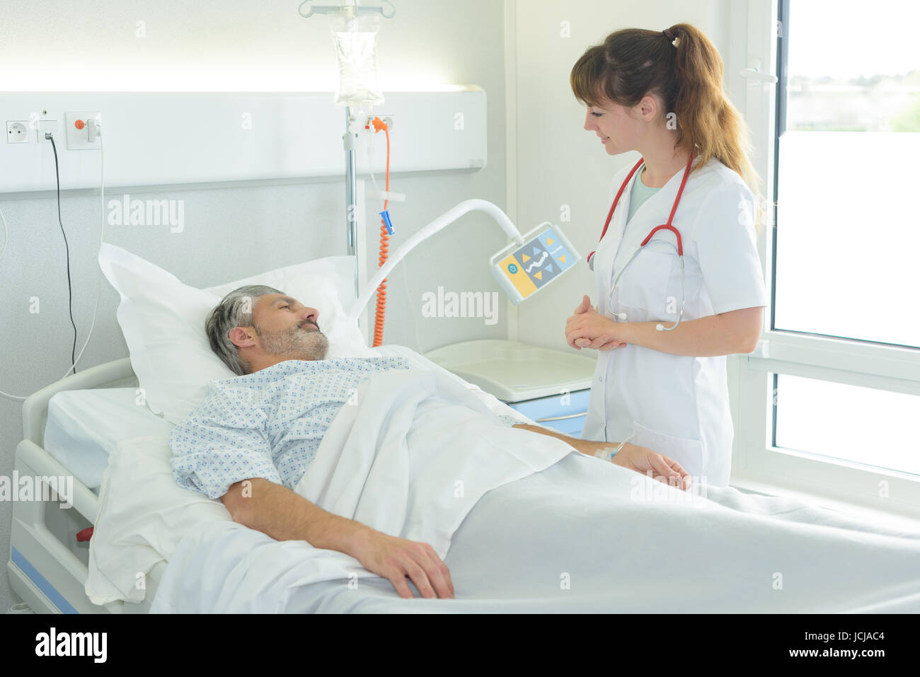 Nurse talking to patient in hospital bed Stock Photo - Alamy