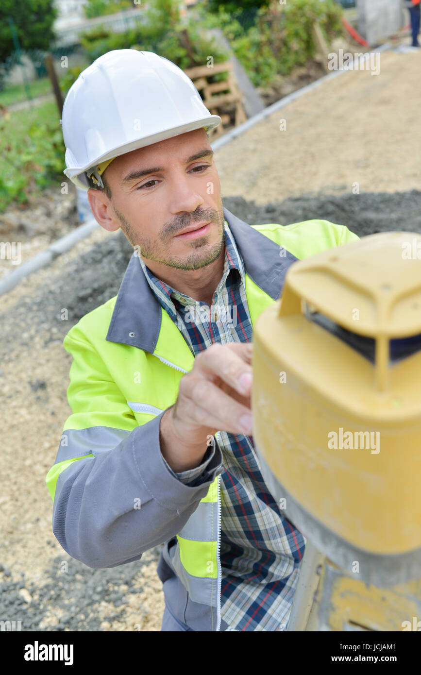 male construction builder taking measurements at construction site ...
