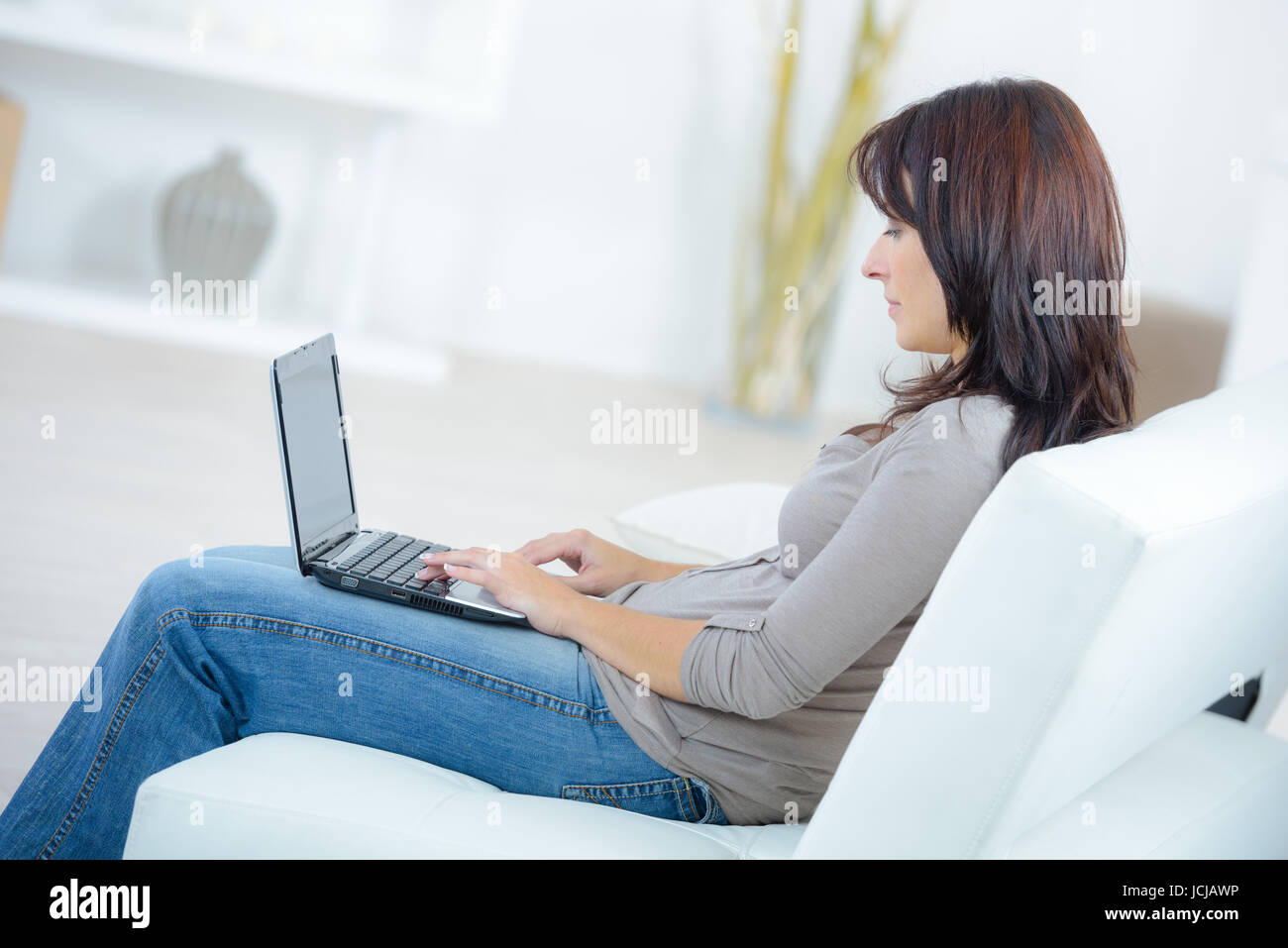 pretty woman sitting on couch with laptop Stock Photo - Alamy