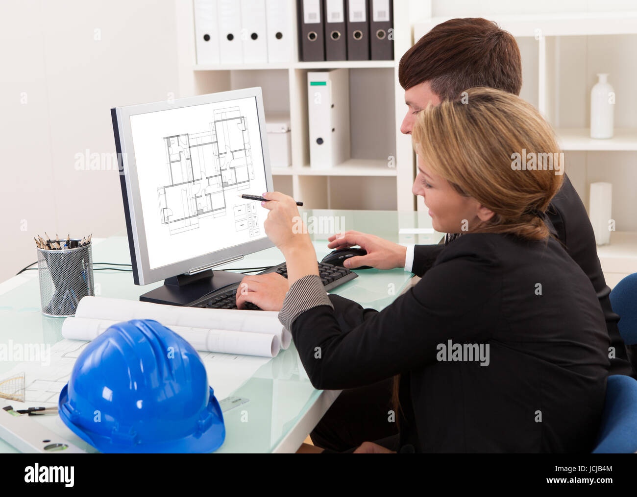 Two professional architects or structural engineers sitting at a desk ...