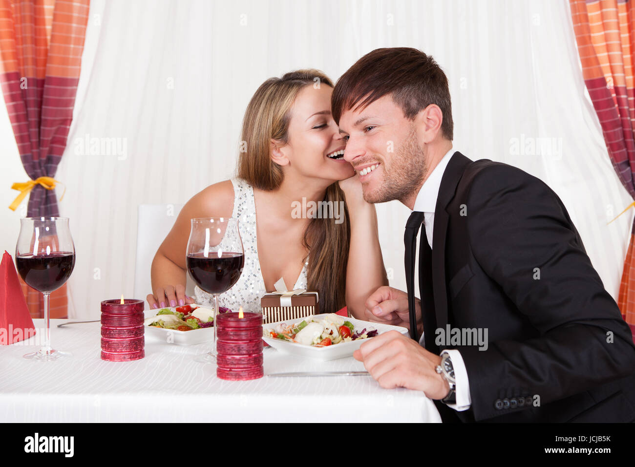 Romantic lovers sitting at an elegant restaurant table enjoying a meal ...