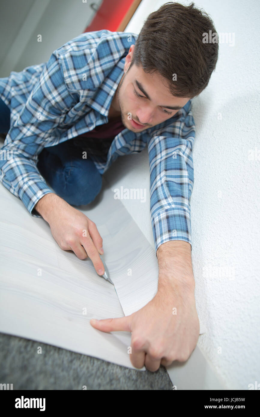 Man cutting underlay against skirting board Stock Photo - Alamy