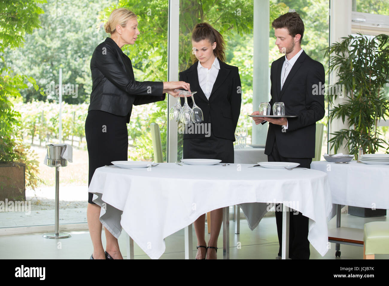 lady teaches hotel students how to properly lay a table Stock Photo - Alamy