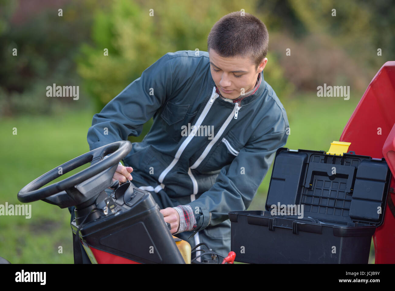 young mechanic fixing something on the tractor Stock Photo - Alamy