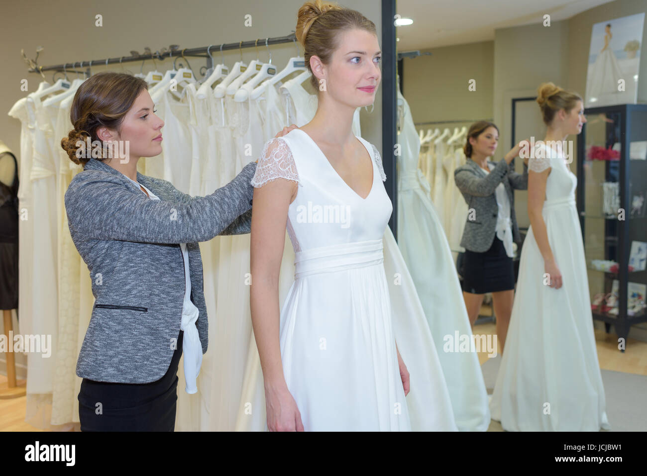 female trying wedding dress in a shop with shop assistant Stock Photo ...