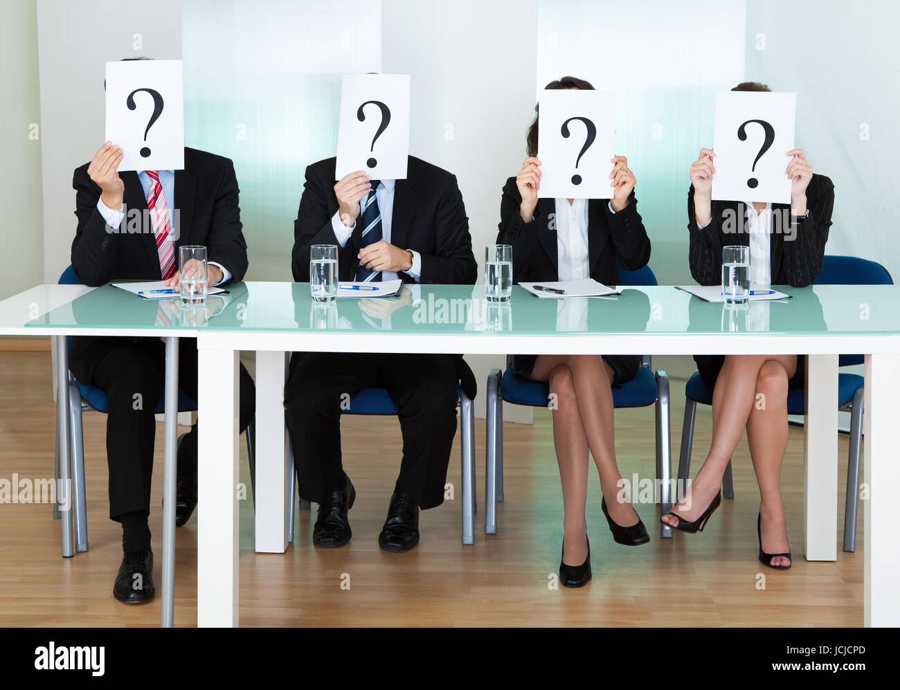 Row of businesspeople with question marks signs in front of their faces ...