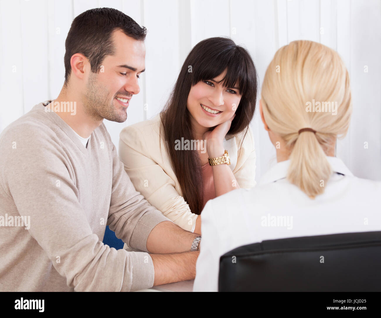 Happy Doctor Discussing With Couple In Clinic Stock Photo - Alamy