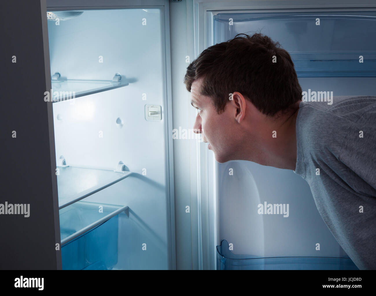 Portrait of a hungry man looking for food in refrigerator Stock Photo ...