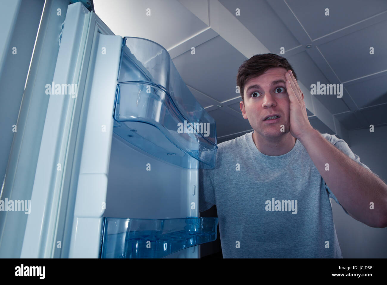 Portrait of a hungry man looking for food in refrigerator Stock Photo ...