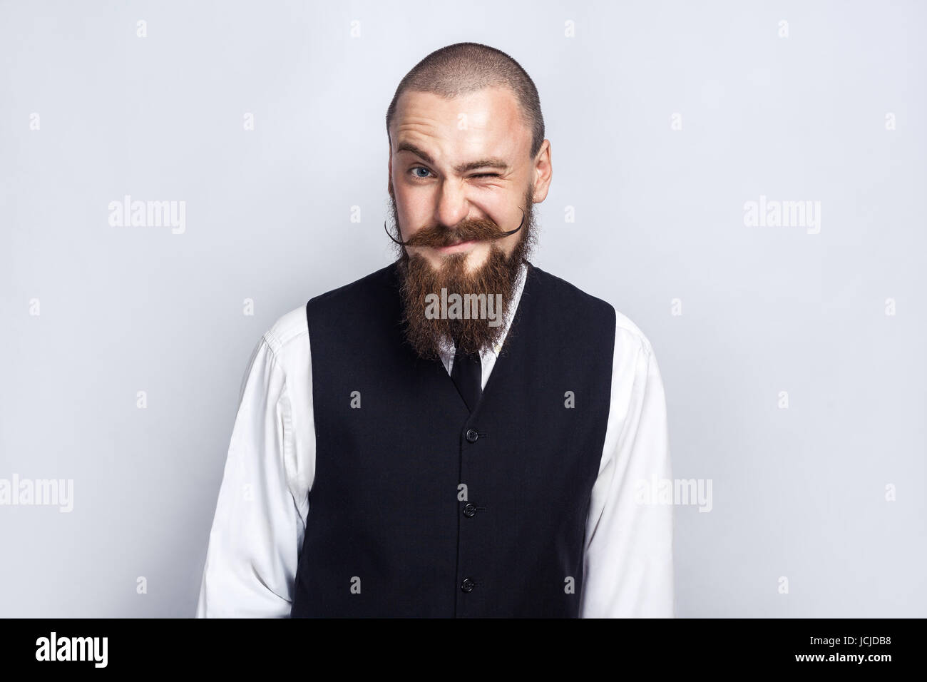 Wink. Handsome businessman with beard and handlebar mustache looking at ...