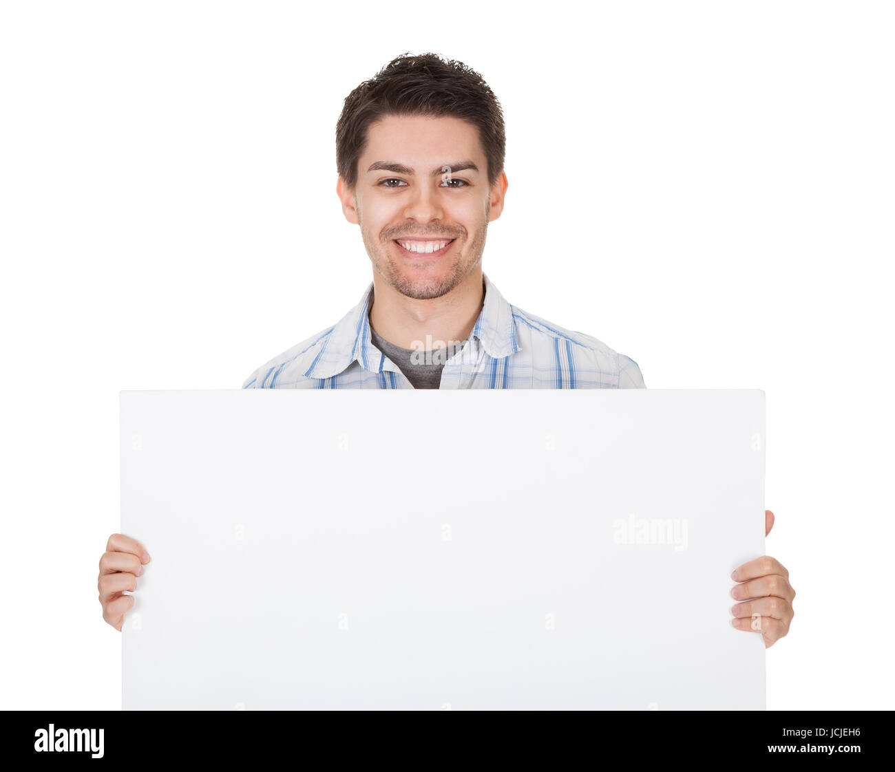 Smiling casual handsome young man holding up a blank white sign in ...