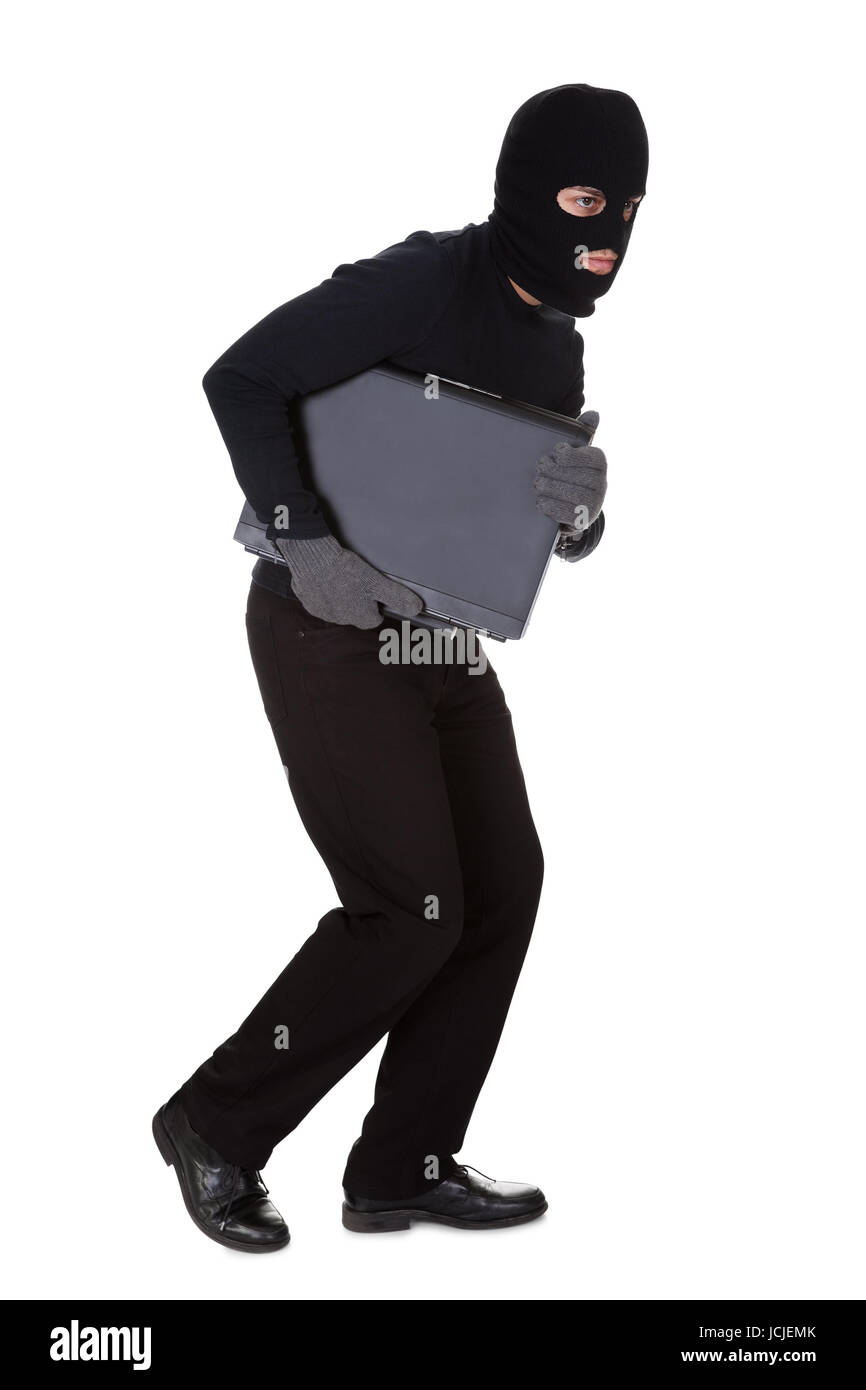 Thief dressed in black and wearing a balaclava stealing a laptop ...