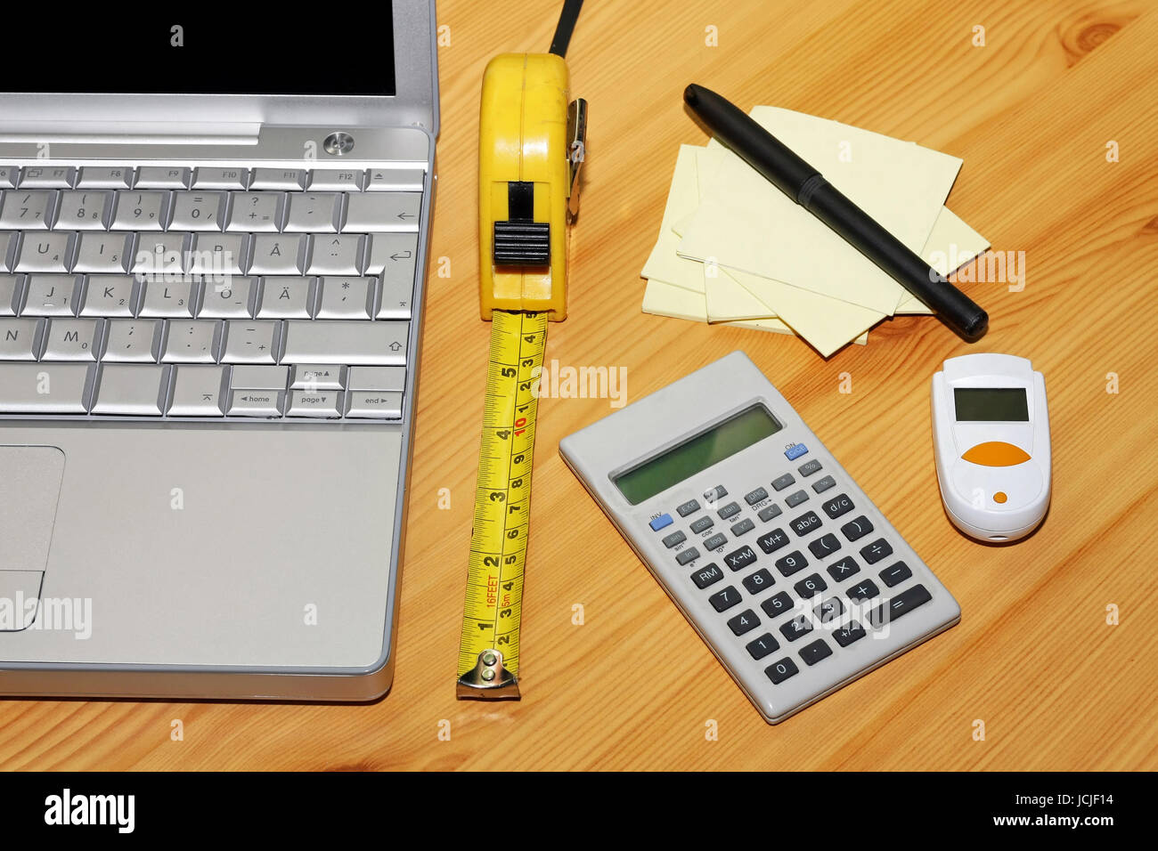 Notebook measuring tape and calculator at wooden desk Stock Photo - Alamy