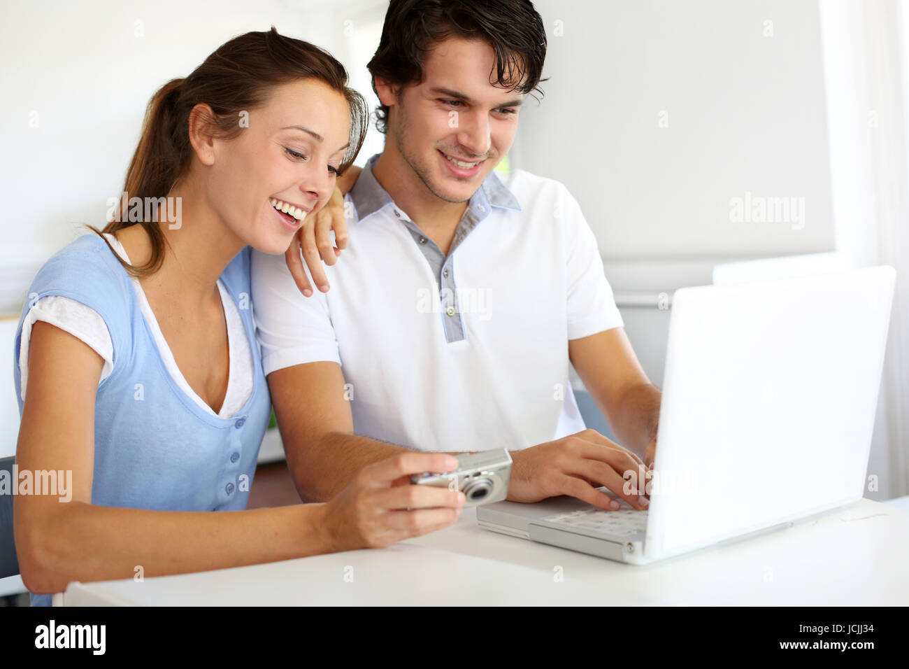 Couple at home uploading photographies on internet Stock Photo - Alamy