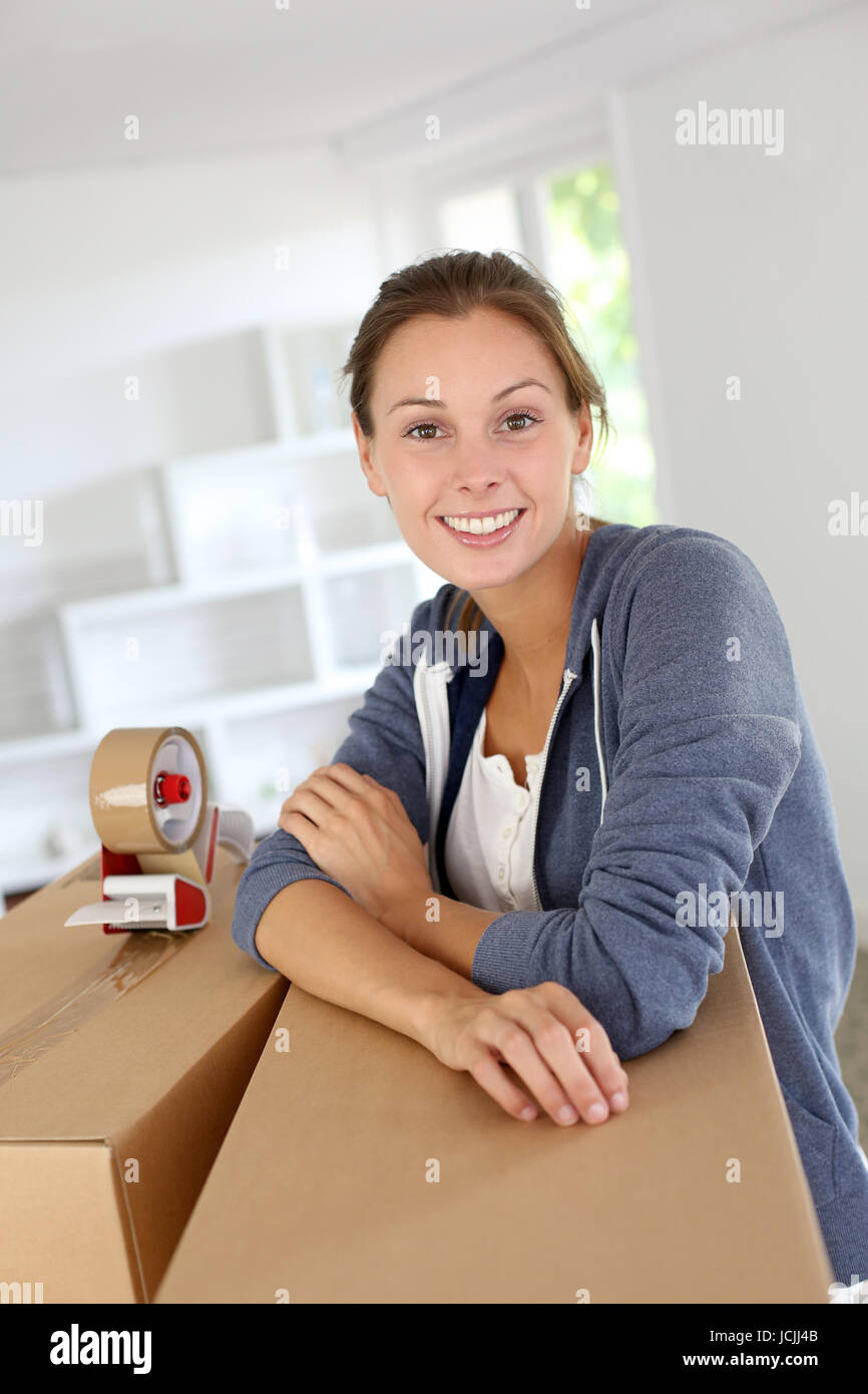 Smiling young woman packing boxes to move out Stock Photo - Alamy